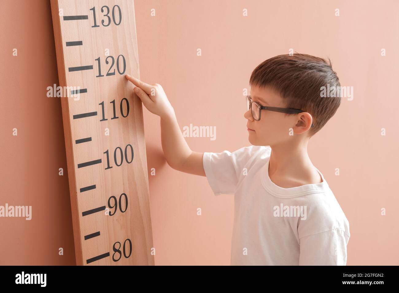 Little boy measuring height near color wall Stock Photo - Alamy