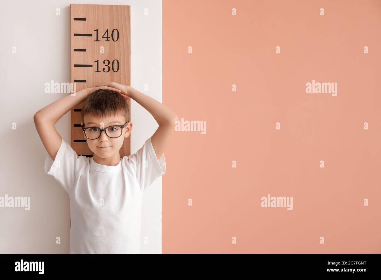 Little boy measuring height near color wall Stock Photo - Alamy