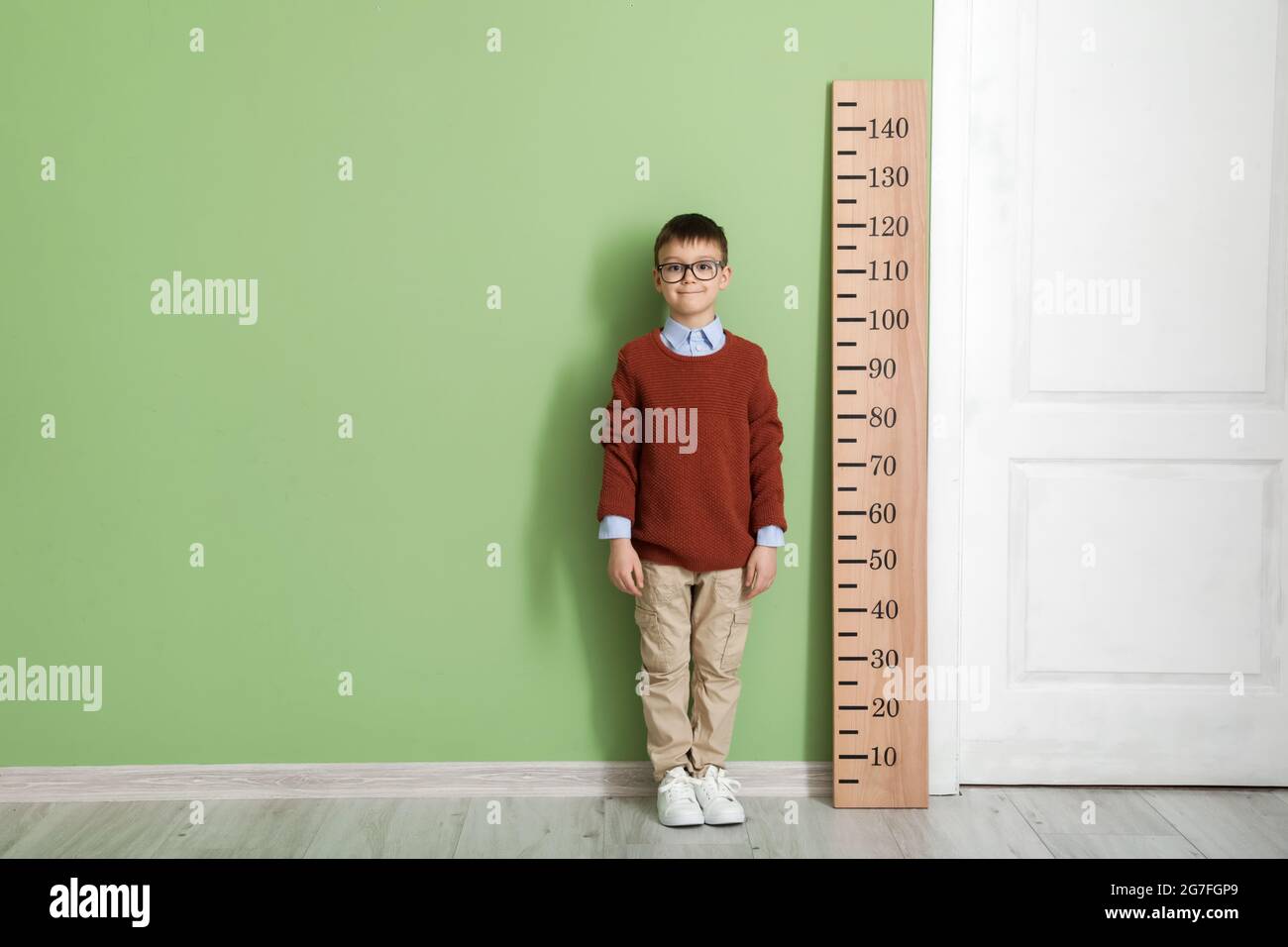 Little boy measuring height near color wall Stock Photo - Alamy