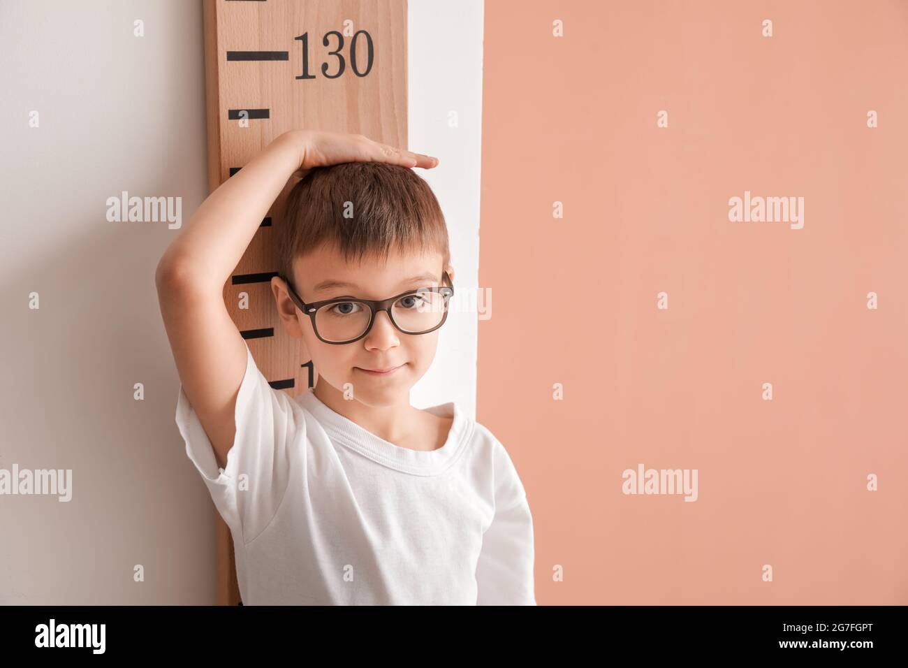 Little boy measuring height near color wall Stock Photo - Alamy