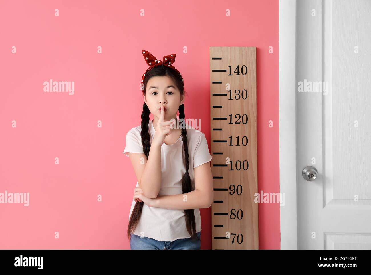 Little girl measuring height near color wall Stock Photo - Alamy