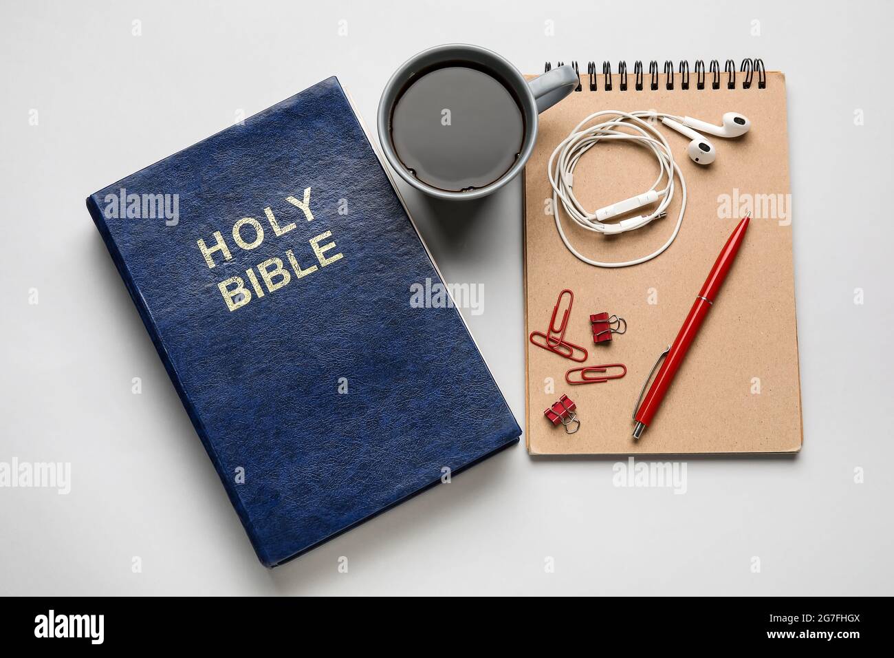 Holy Bible, cup of coffee, earphones and notebook on light background ...