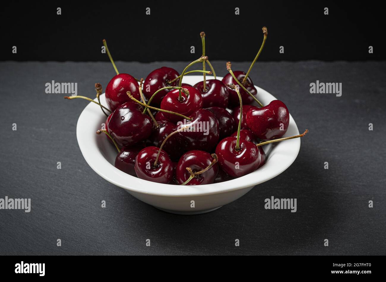 Closeup shot of fresh cherries in a bowl on a black surface Stock Photo ...