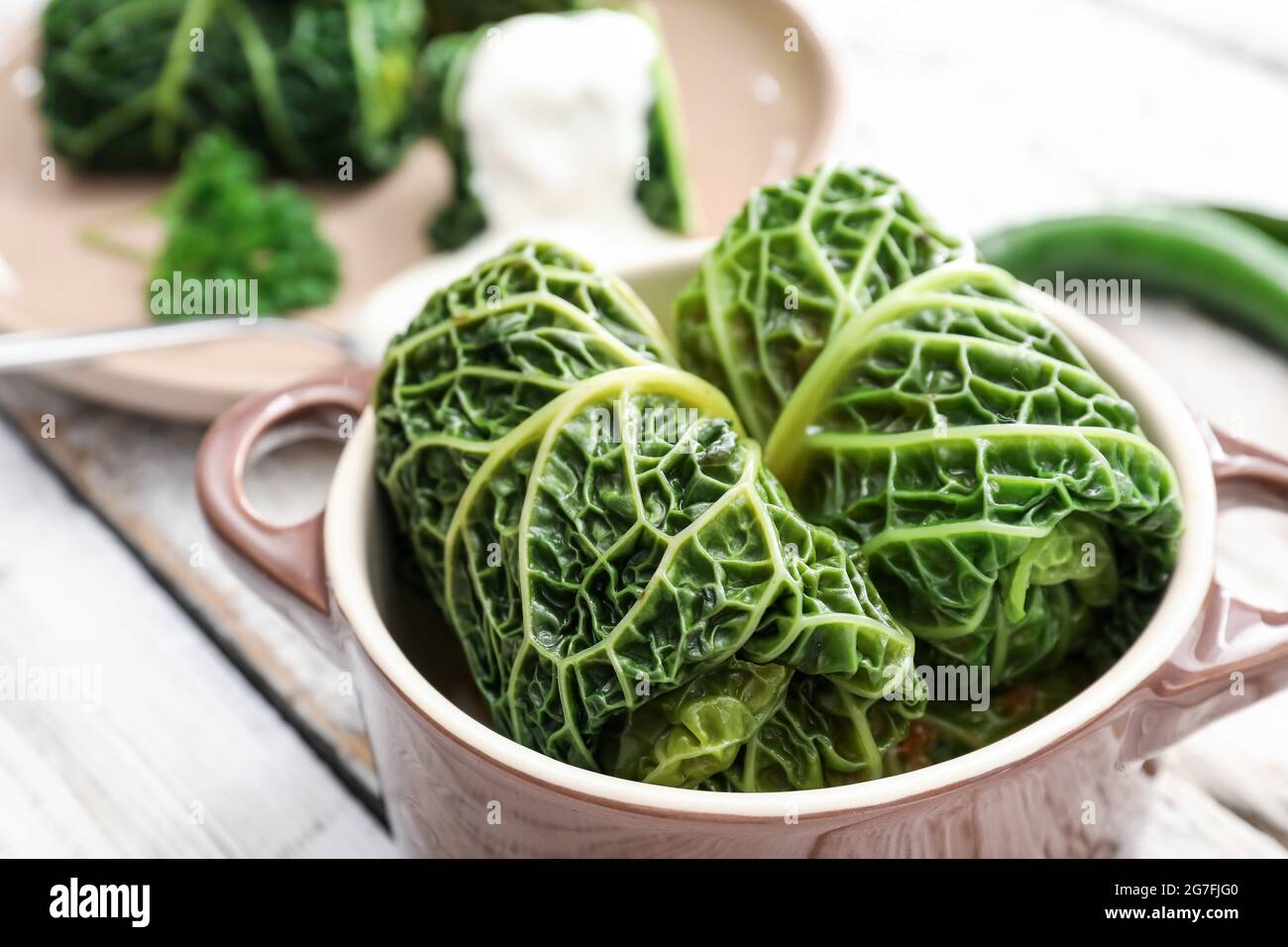 Cooking pot with stuffed cabbage leaves on light wooden background ...