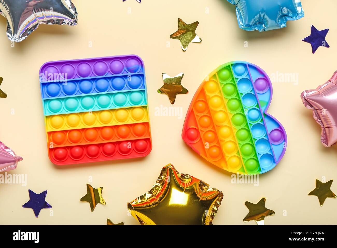 Pop it fidget toys and balloons on color background Stock Photo - Alamy