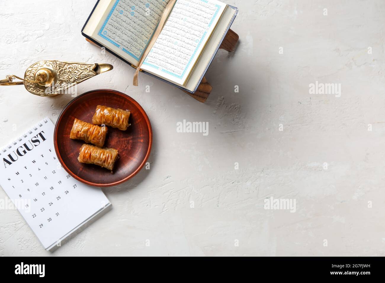 Composition with sweets, lamp, calendar and Koran on light background ...