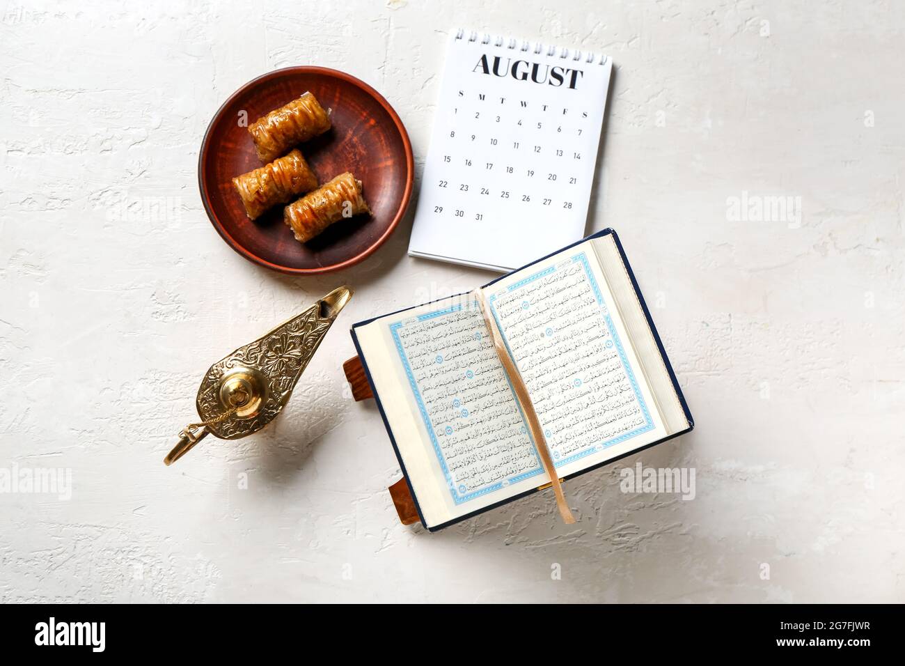 Composition with sweets, lamp, calendar and Koran on light background ...
