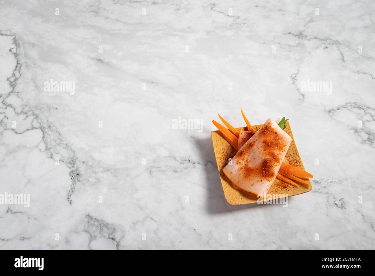 Delicious appetizer on a small wooden plate on a marble texture table ...