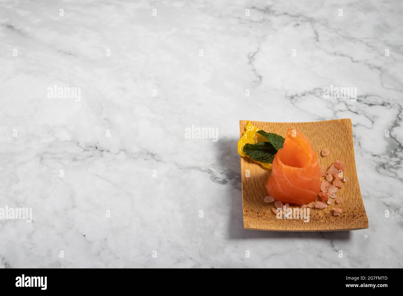 Delicious appetizer on a small wooden plate on a marble texture table ...