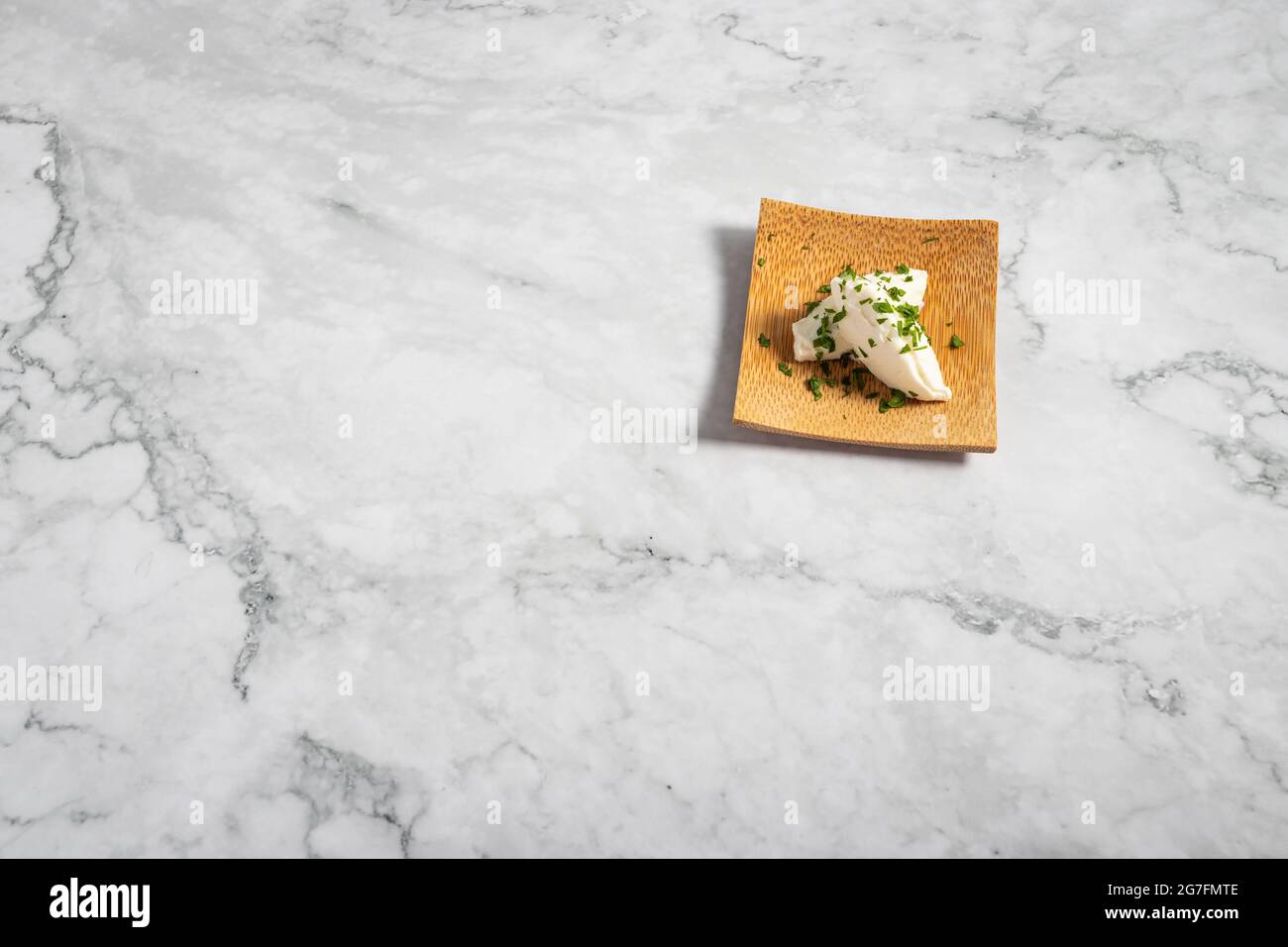 Delicious appetizer on a small wooden plate on a marble texture table ...