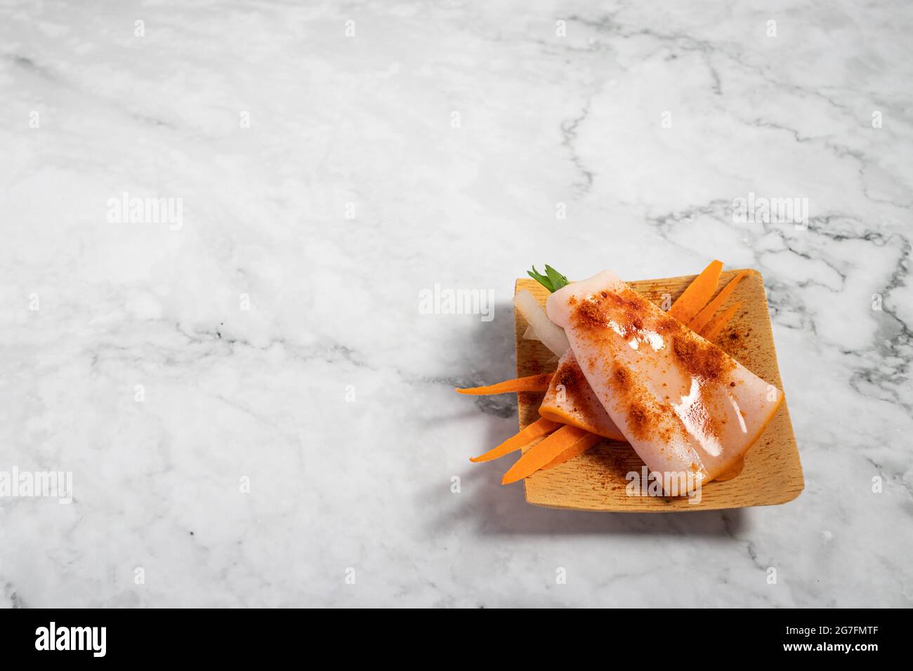 Delicious appetizer on a small wooden plate on a marble texture table ...