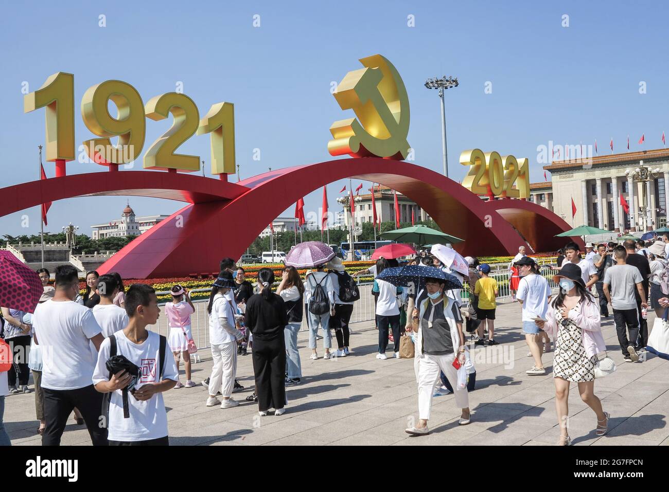 Tourists walk under the Communist Party emblem in Beijing's Tiananmen ...