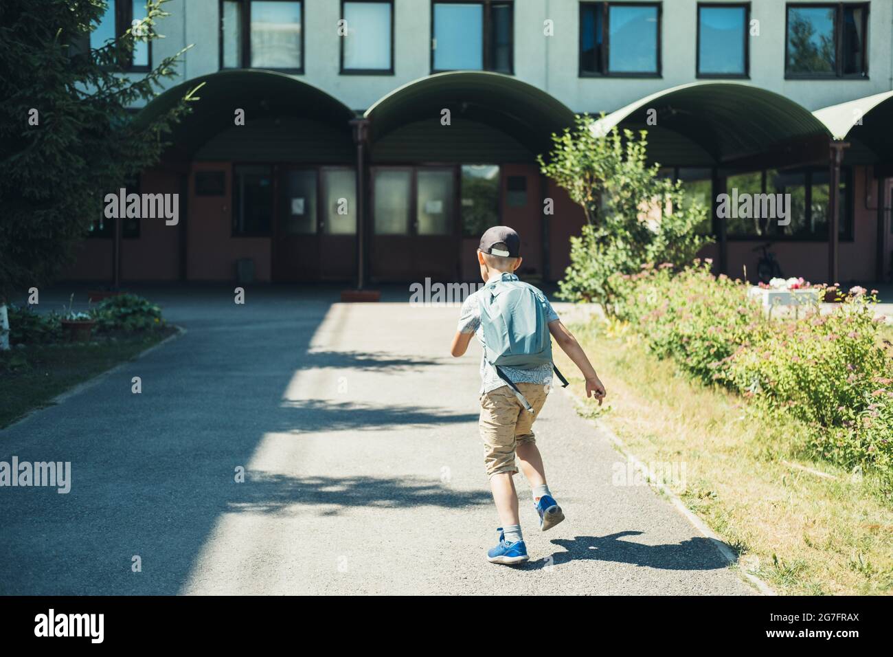 The boy, elementary school student, walking to school with bag behind ...