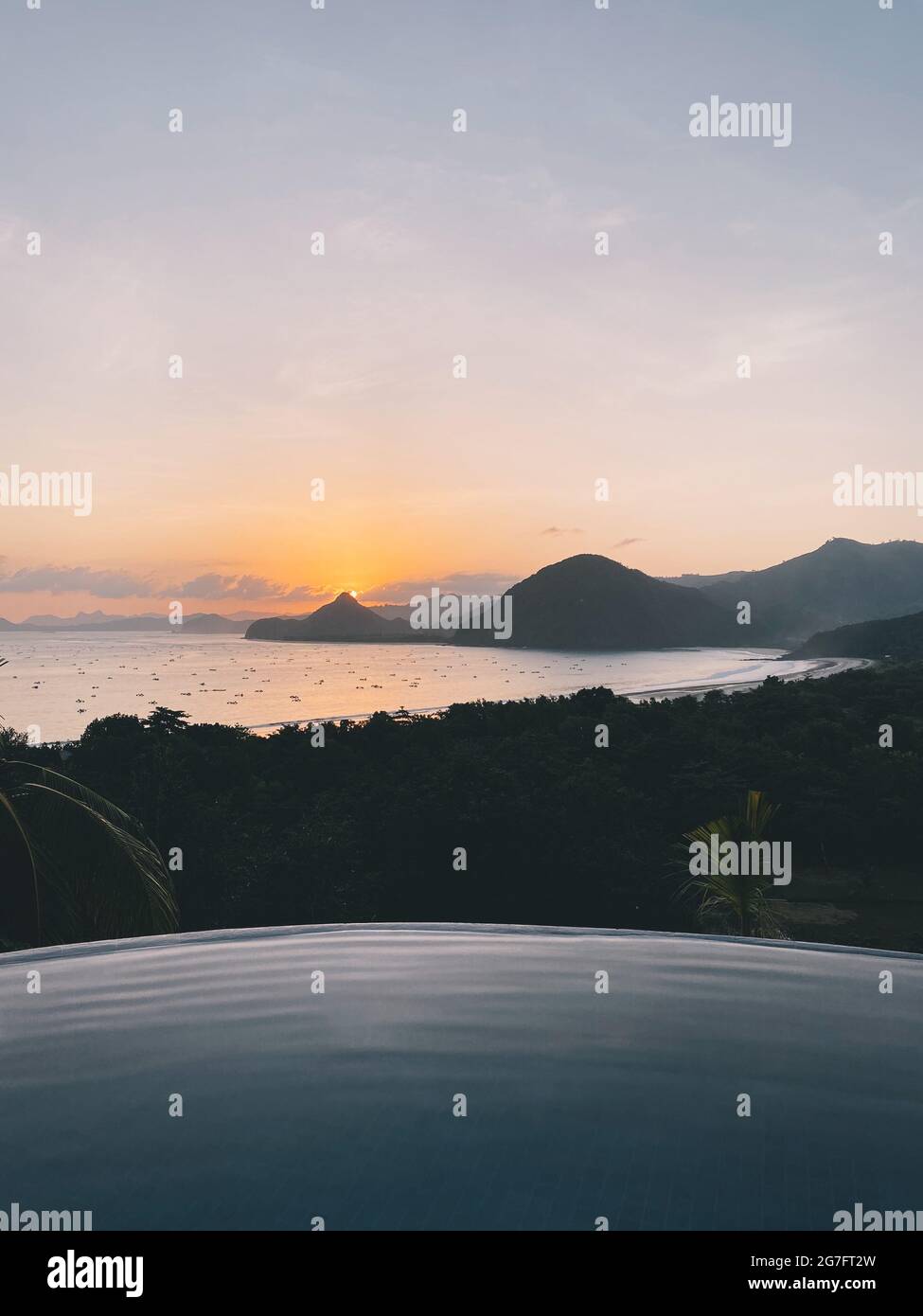 Luxury infinity pool overlooking tropical beach lagoon during sunset ...
