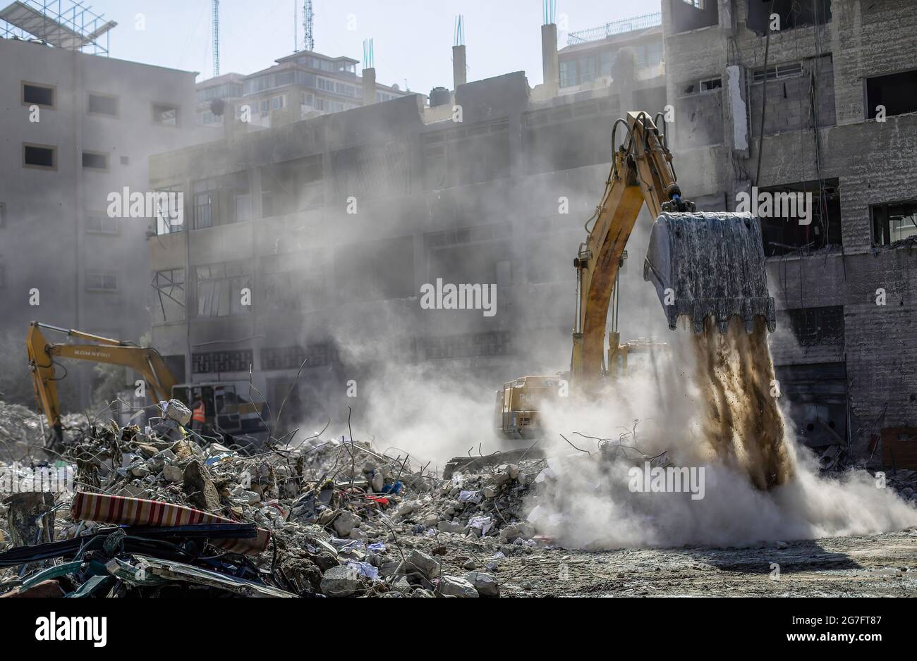 An excavator clears the rubble of destroyed towers and houses following ...