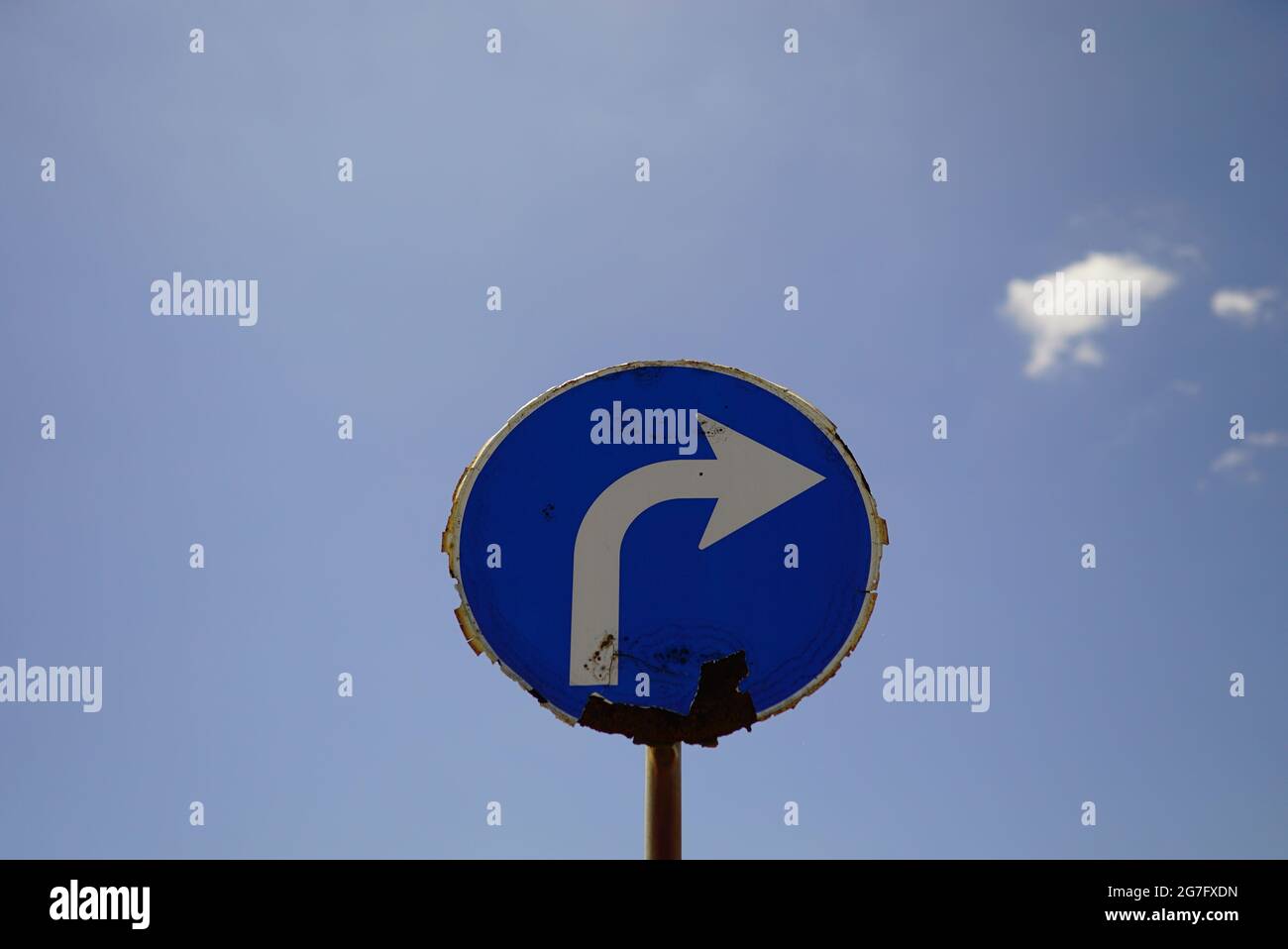 Road sign showing a right turn on blue sky background Stock Photo - Alamy