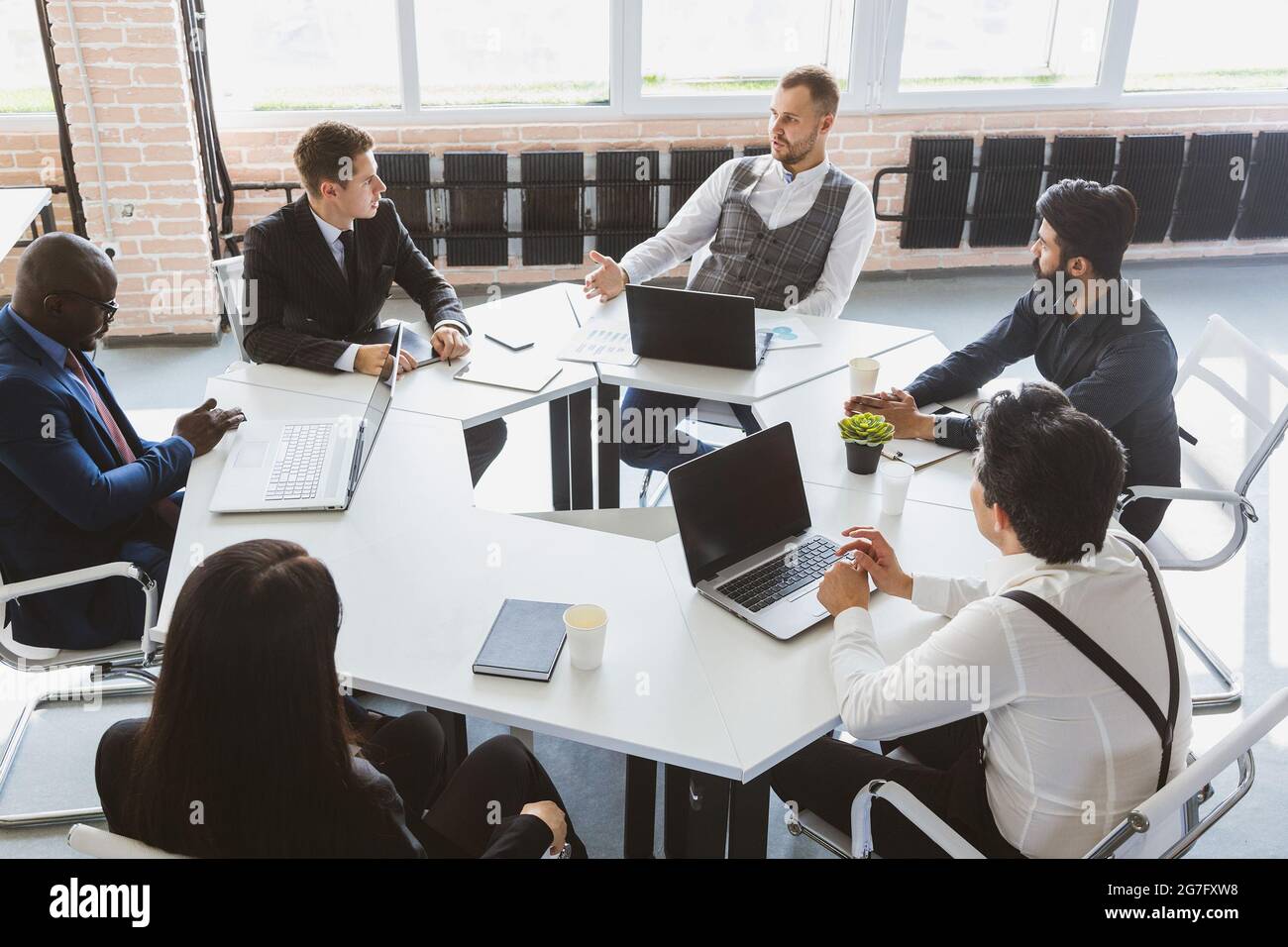 Group of young business people working and communicating while sitting ...