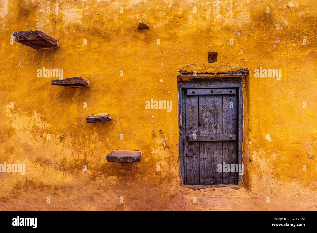 Old brown wooden door with stairs in yellow traditional mud wall at ...
