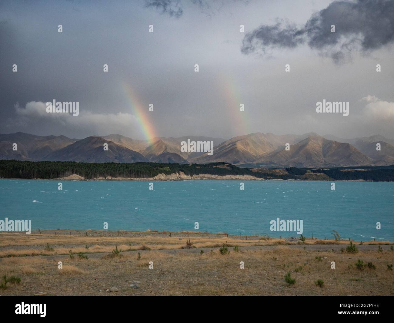 View of a colorful double rainbow over a mountain range and lake Stock ...