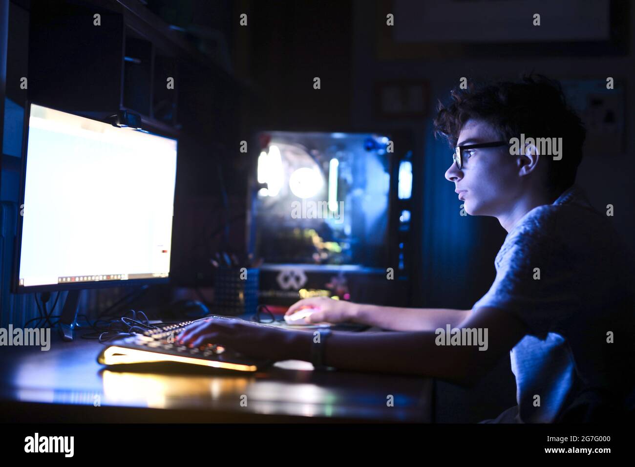 Shot of a Caucasian young boy playing on computer in a dark room Stock ...