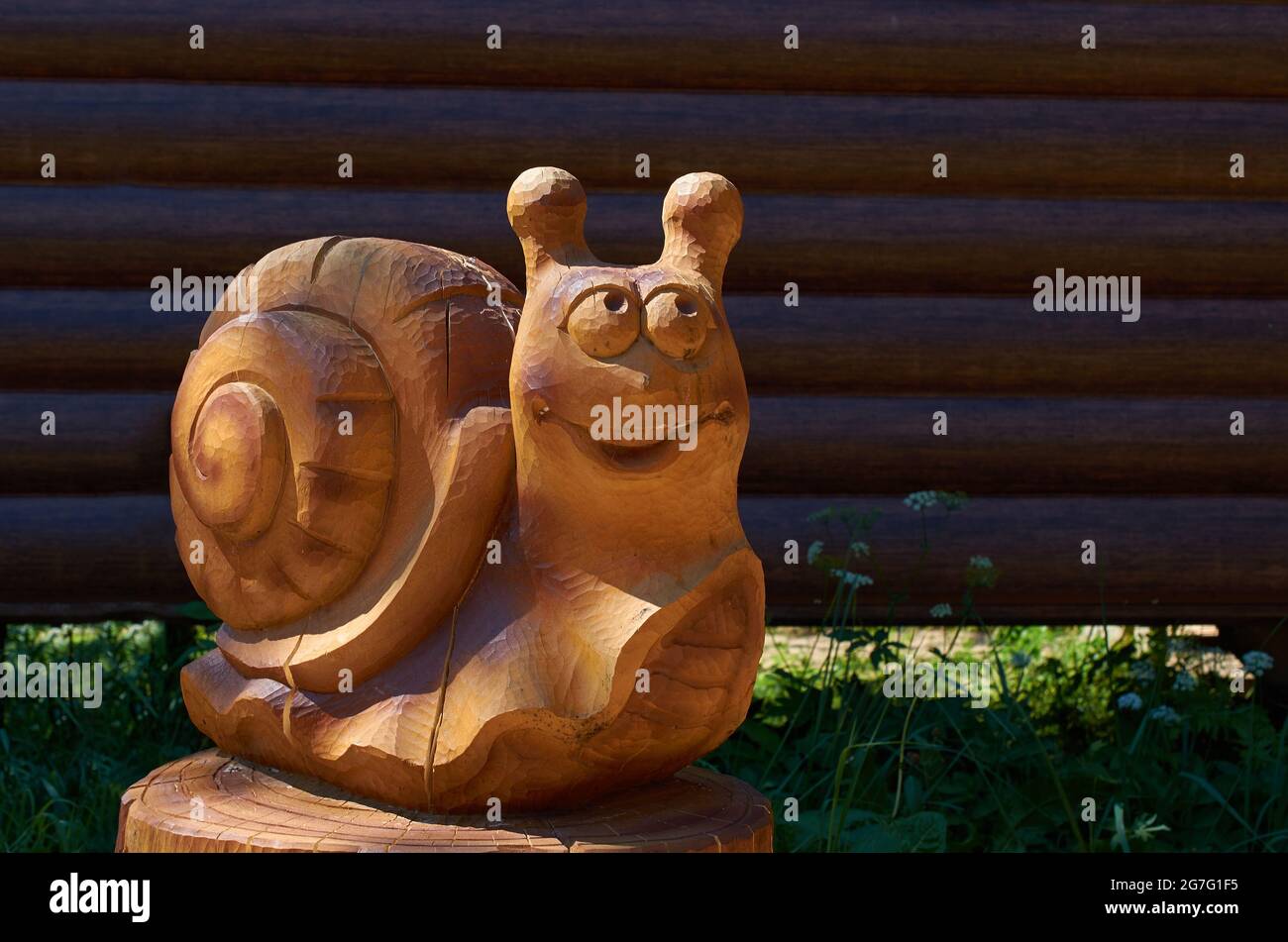 A wooden statue of a snail on a stump, isolated on a white background ...
