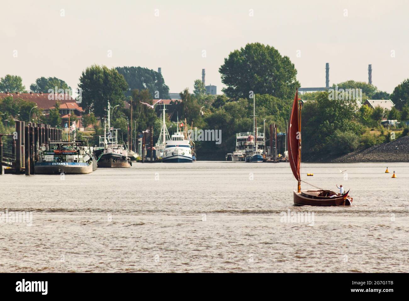 Sailing boat crossing river with sail up Stock Photo - Alamy