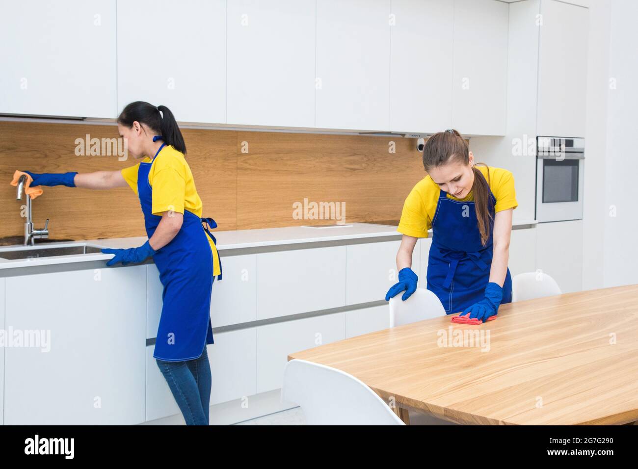 professional cleaning service. Two women in working uniform, in aprons ...