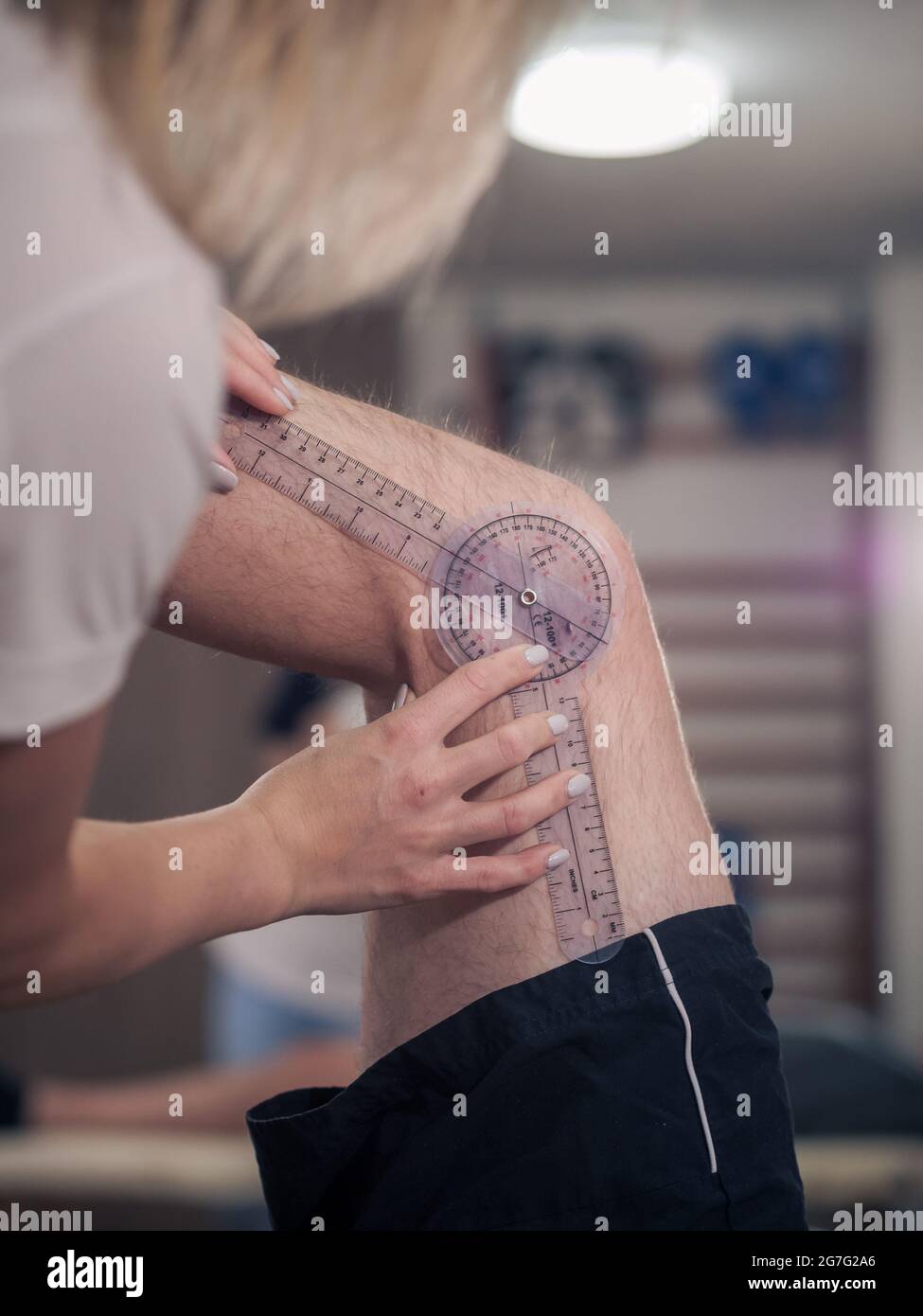 Physiotherapy indoors in a room. One young physiotherapist measuring ...