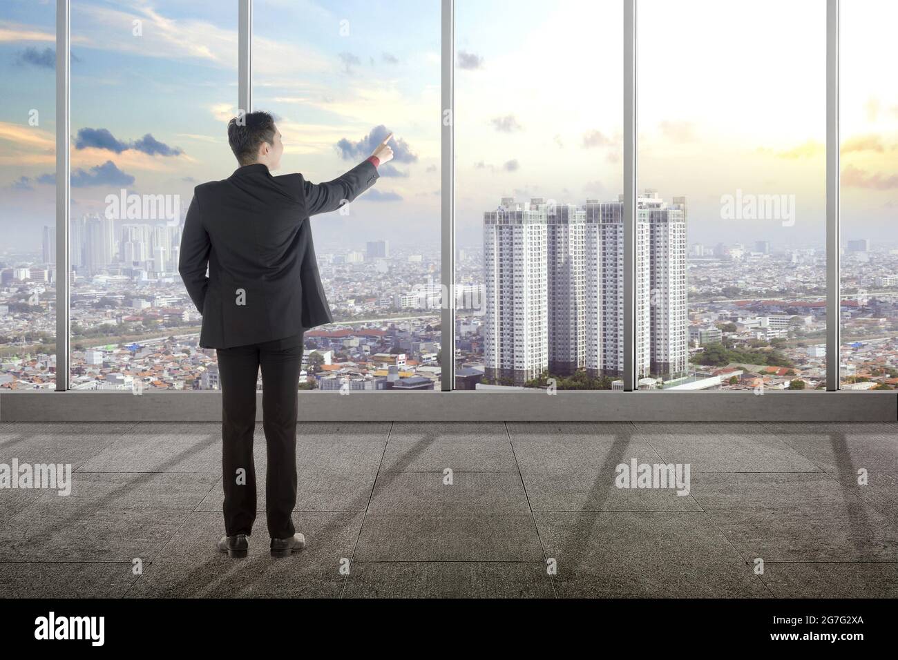 Rear view of Asian businessman pointing through the window on the ...