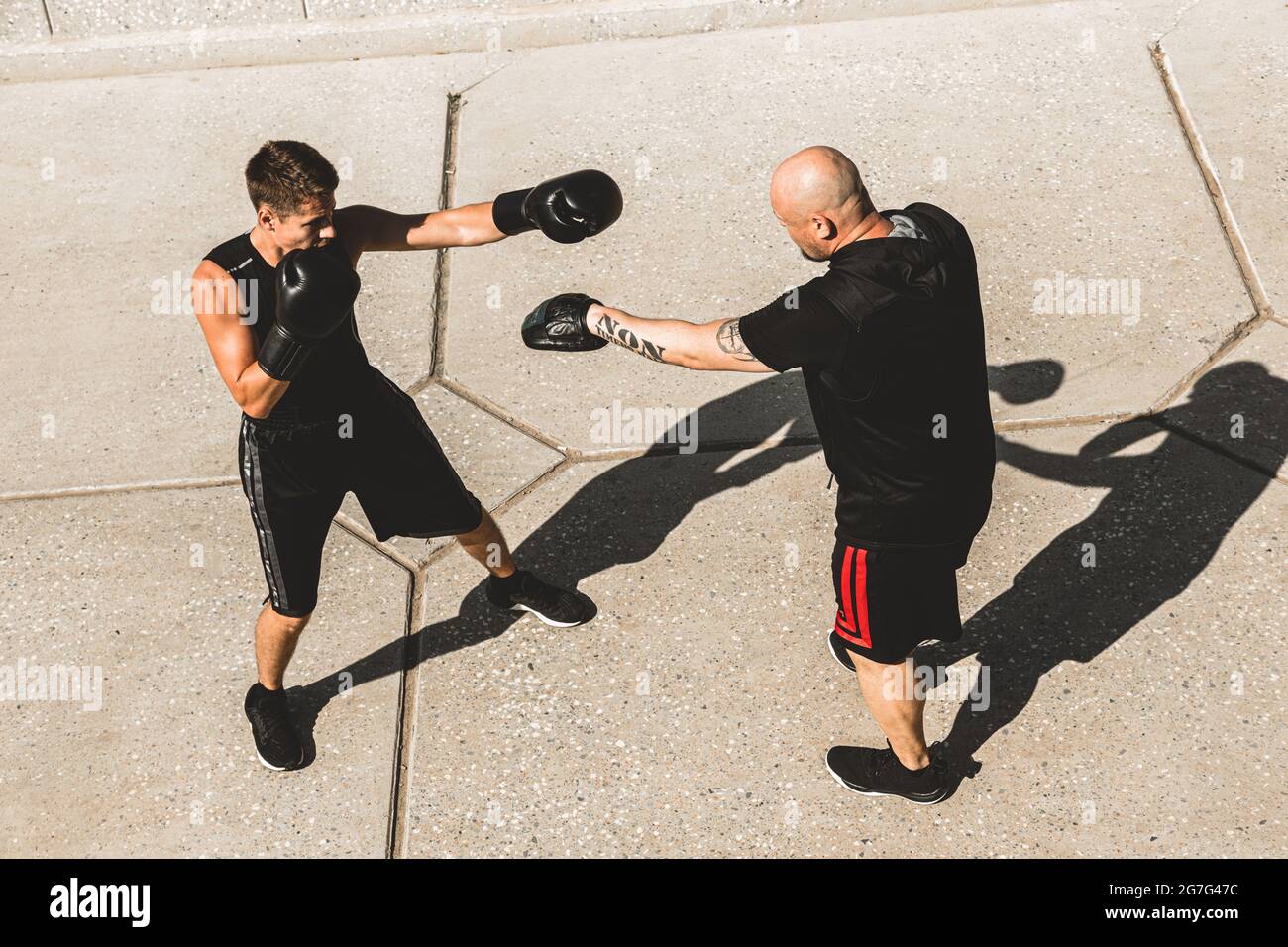 Two men exercising and fighting in outside. Boxer in gloves is training ...