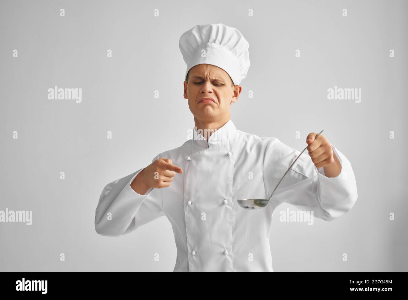 a man in a chef's uniform points a finger at a ladle Stock Photo - Alamy