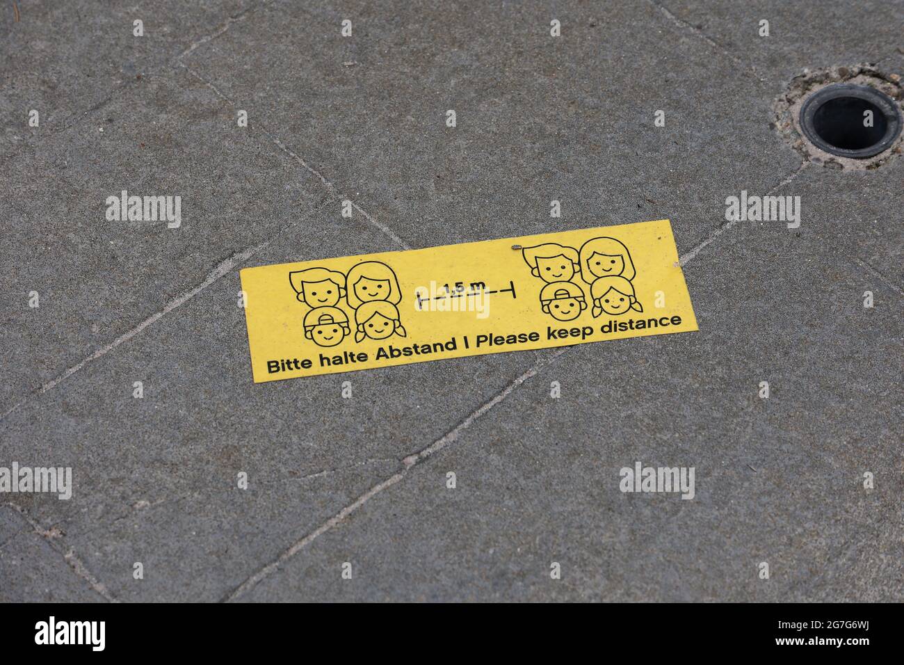 "Please keep distance" information sign on the sidewalk during ...