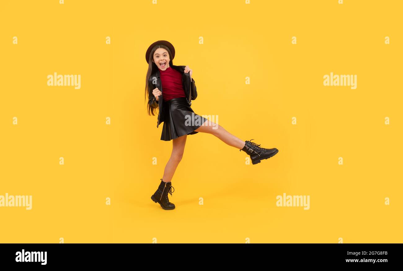 happy teen girl in hat and leather clothes making wide step forward, go ...