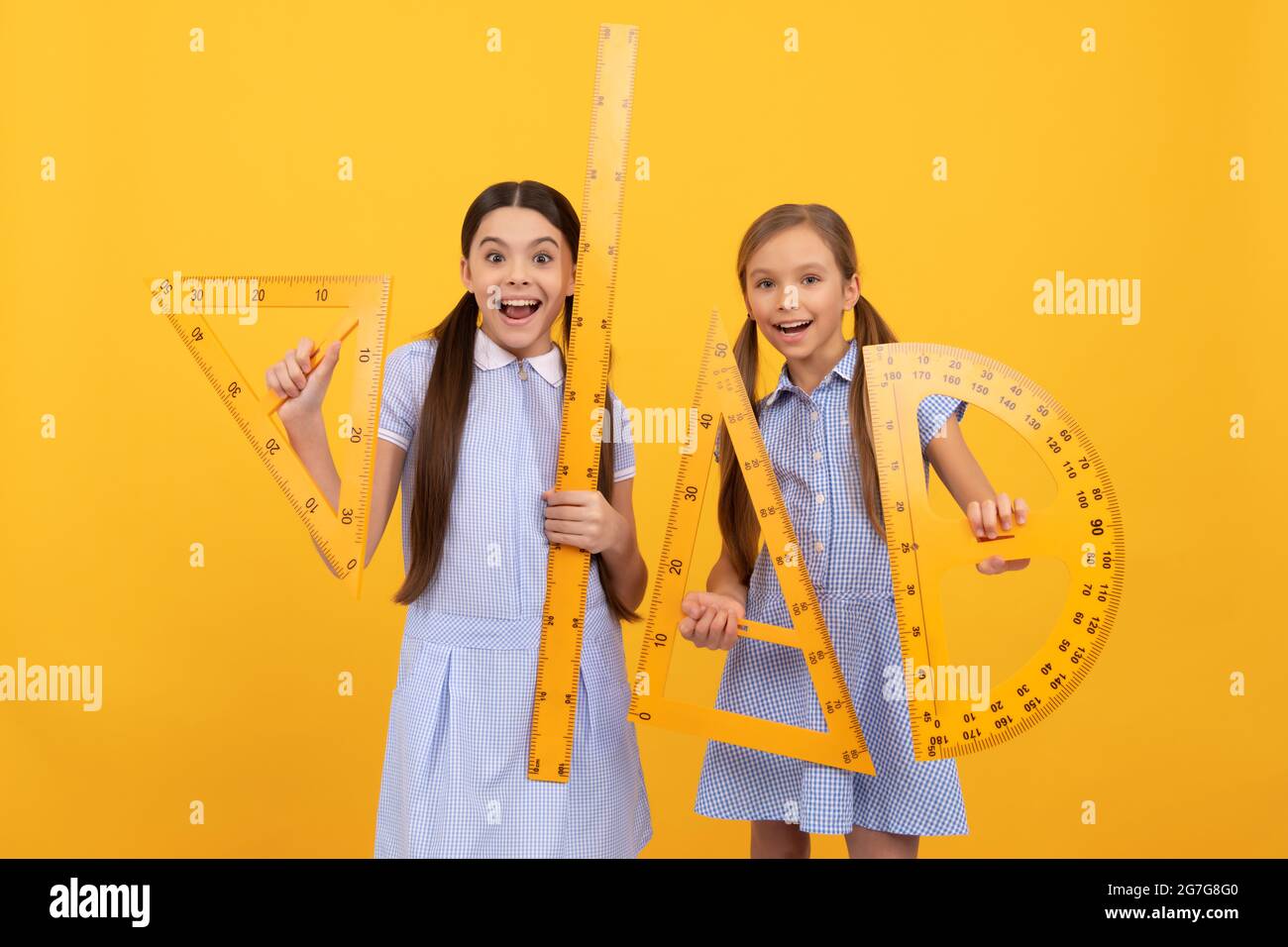 Back to school is here. Happy schoolgirls hold geometric tools. Back to ...