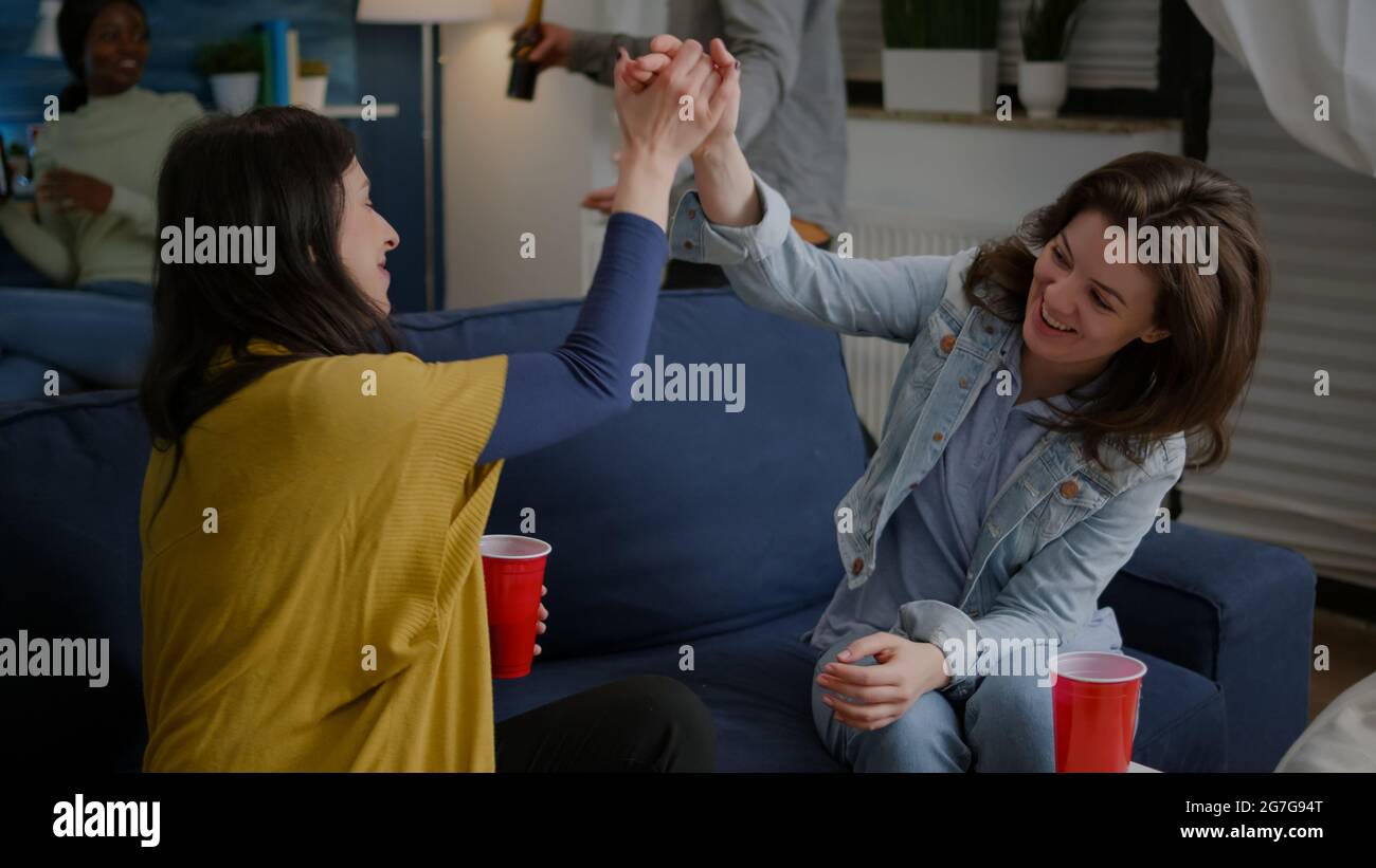 Cheerful women celebrating friendship with high five late at night in ...