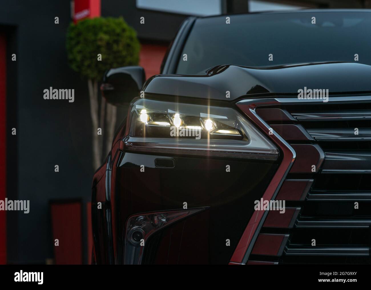 Close up front view of black color modern crossover. Front illuminated ...