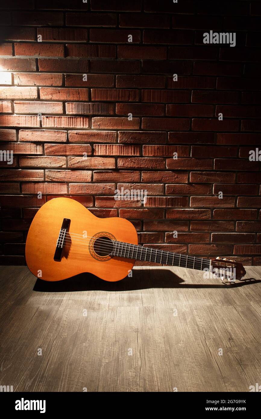 Vertical classical guitar on brick background with diagonal lighting ...
