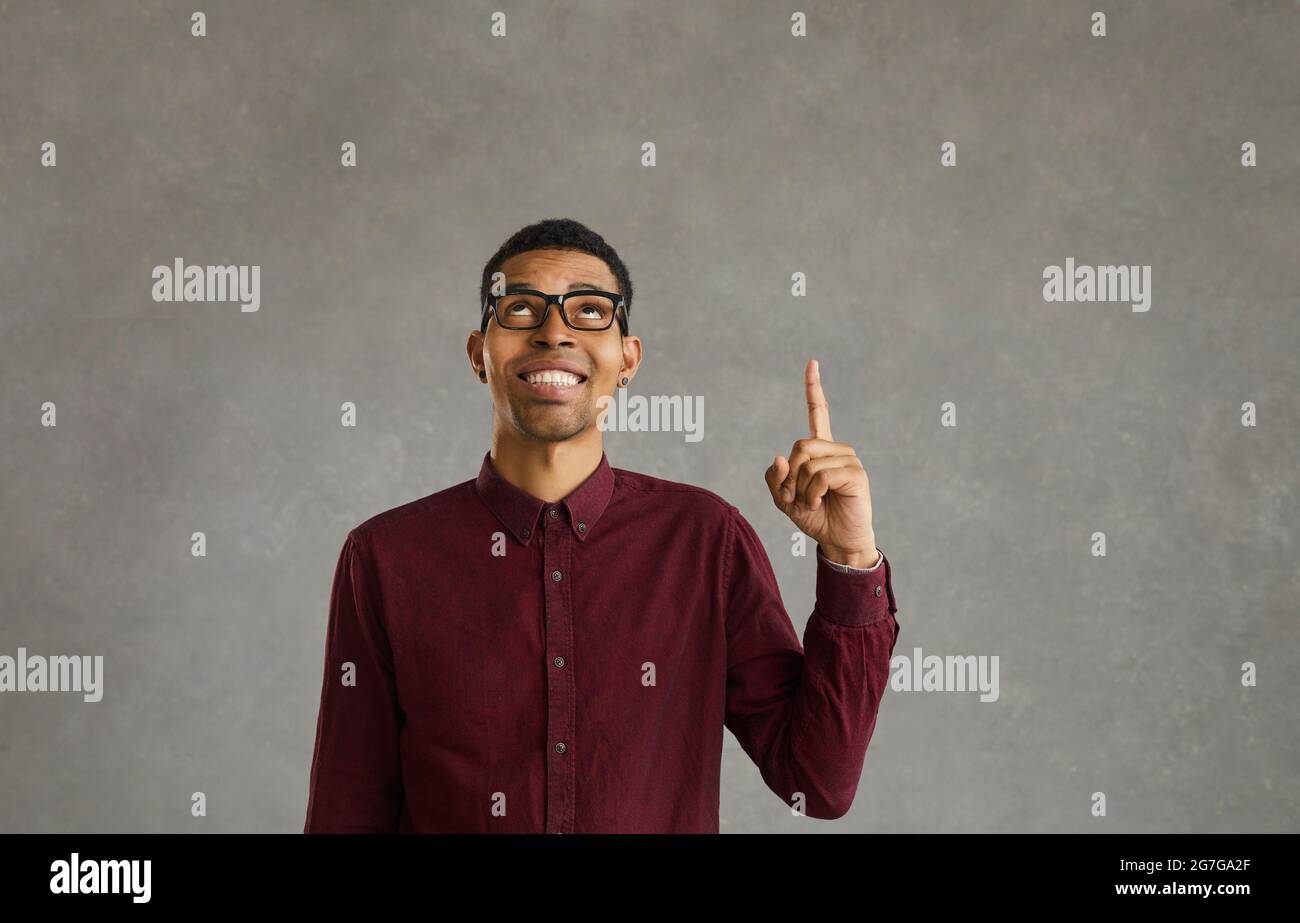 African american young man looking and pointing finger at empty space ...