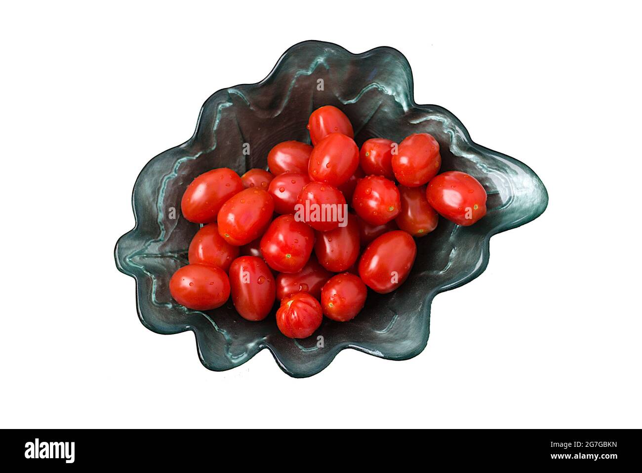 Small red Roma tomatoes in a green glass bowl on a white background ...