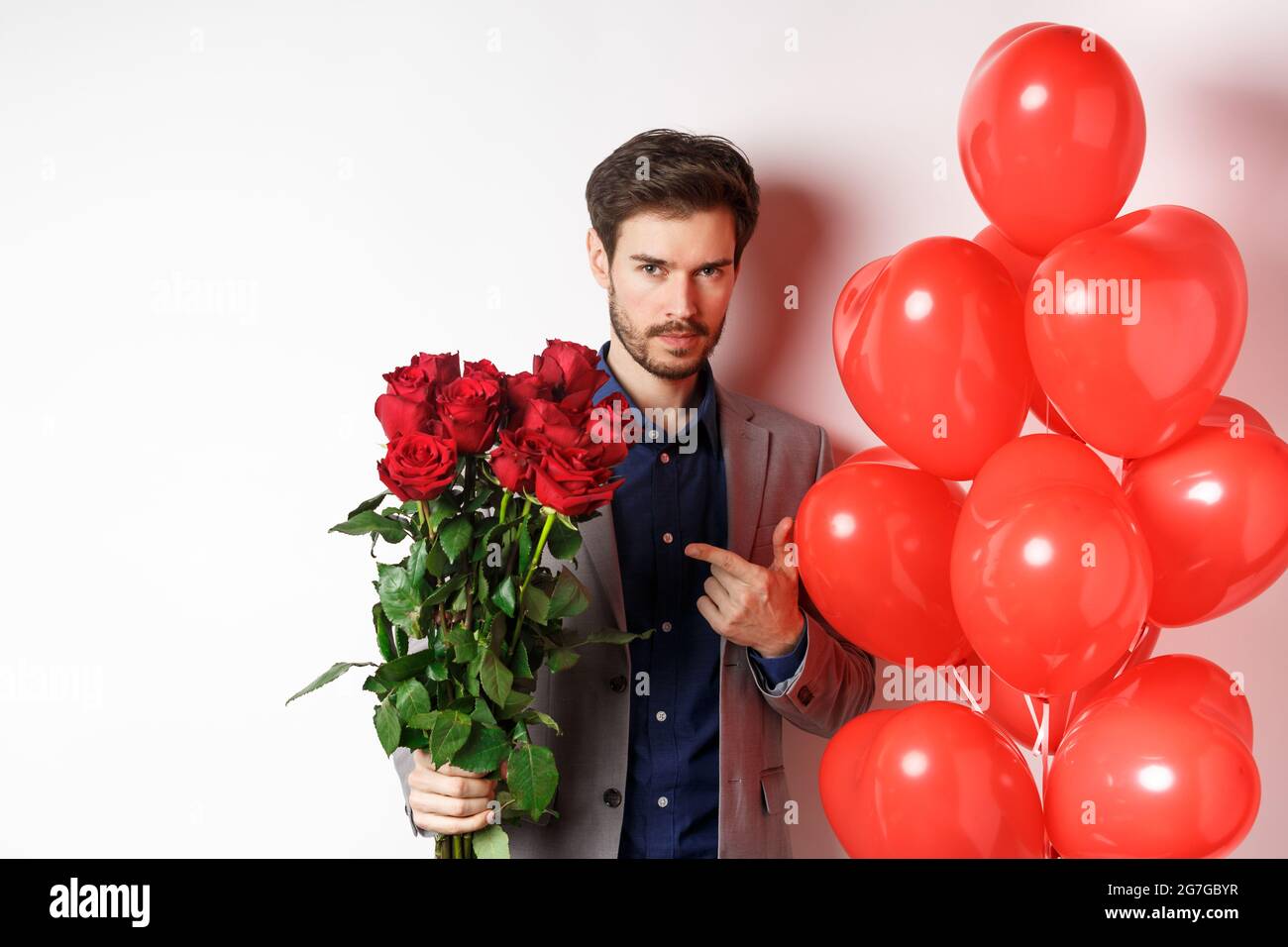 Handsome man in suit going on romantic Valentines day date, pointing at ...