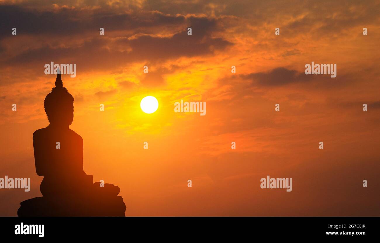 Silhouette Buddha on a sunset background shining from behind Stock ...