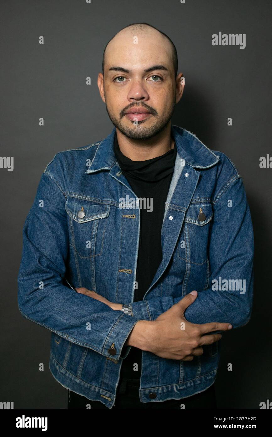 Portrait of a young handsome Mexican bald man wearing a denim jacket ...