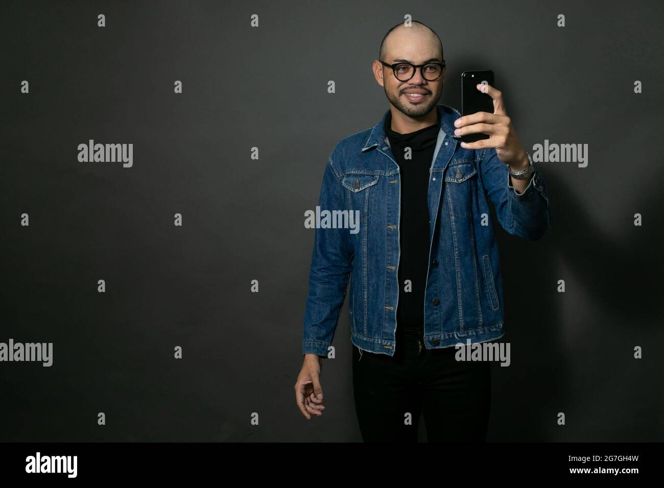 Portrait of a young handsome Mexican bald man with glasses taking a ...