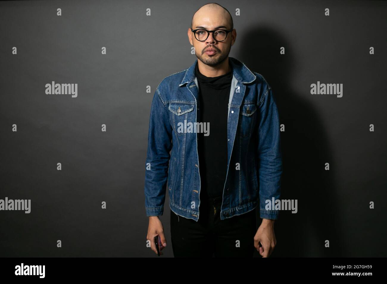 Portrait of a young handsome Mexican bald man with glasses posing ...