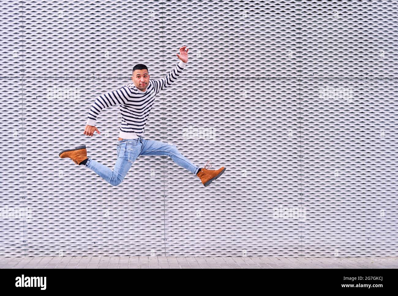 Full body excited Hispanic male smiling and leaping over pavement ...