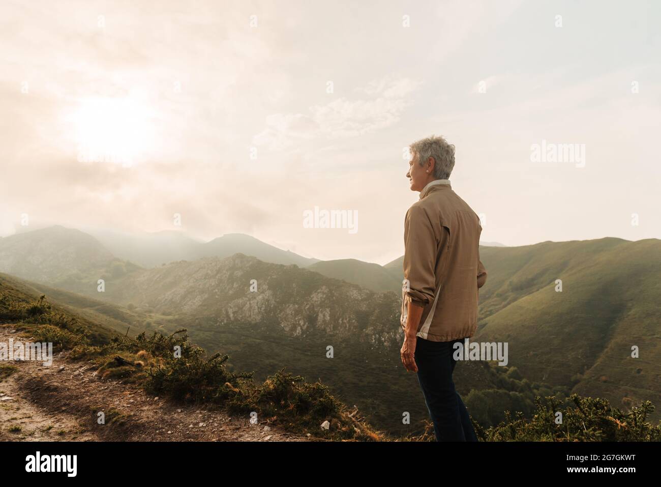 Back view of standing senior Woman explorer admiring mountainous ...