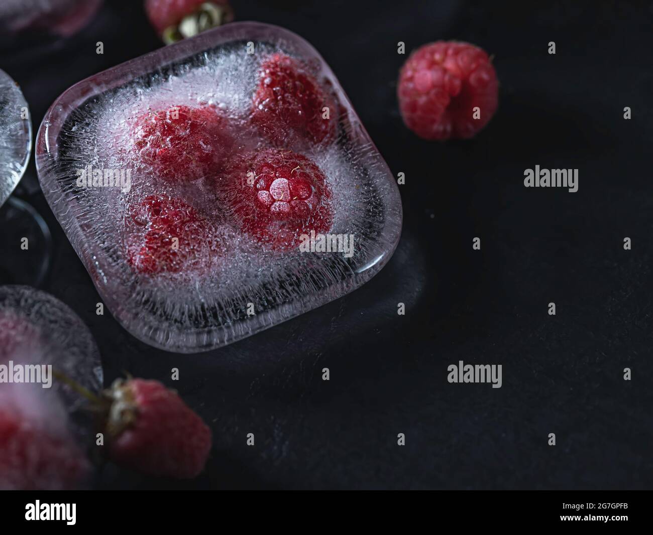 Raspberry frozen in the ice cube on black background. Fresh healthy ...