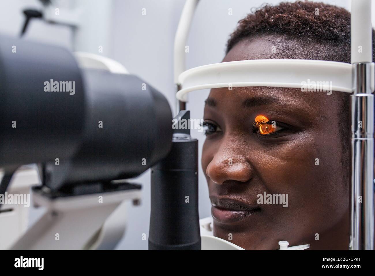 Optometrist adjusting the retinograph during study of the eyesight of a ...