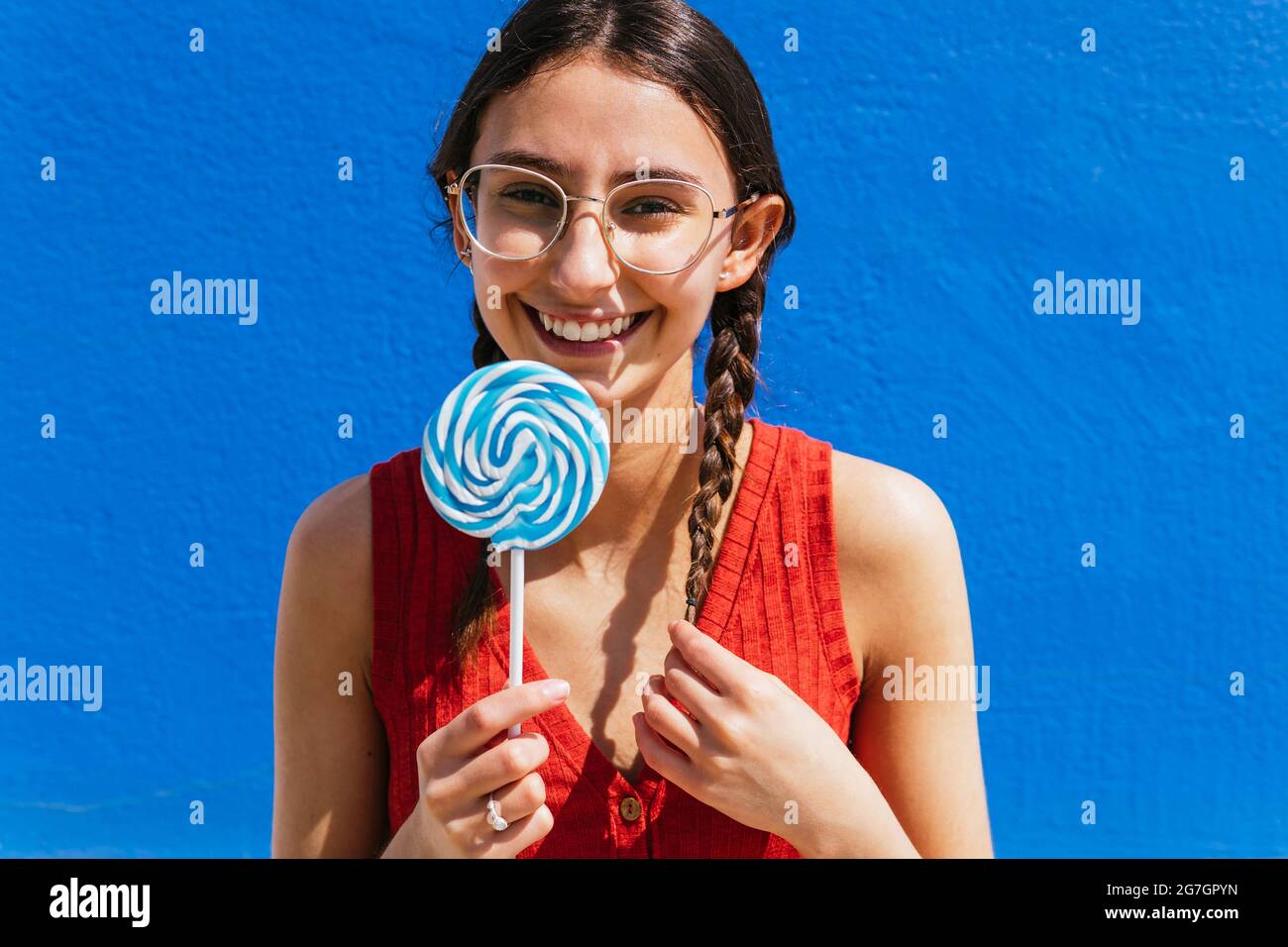 Positive charming female standing with sweet lollipop in street on ...