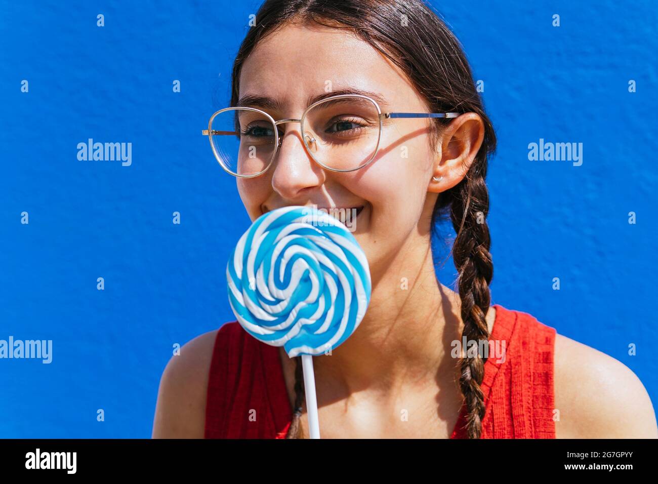 Positive charming female standing with sweet lollipop in street on ...
